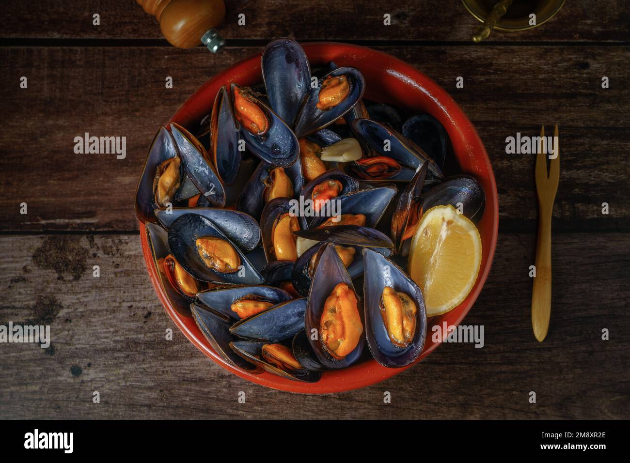 Steamed mussels with lemon in clay pot with metal mortar and pepper ...