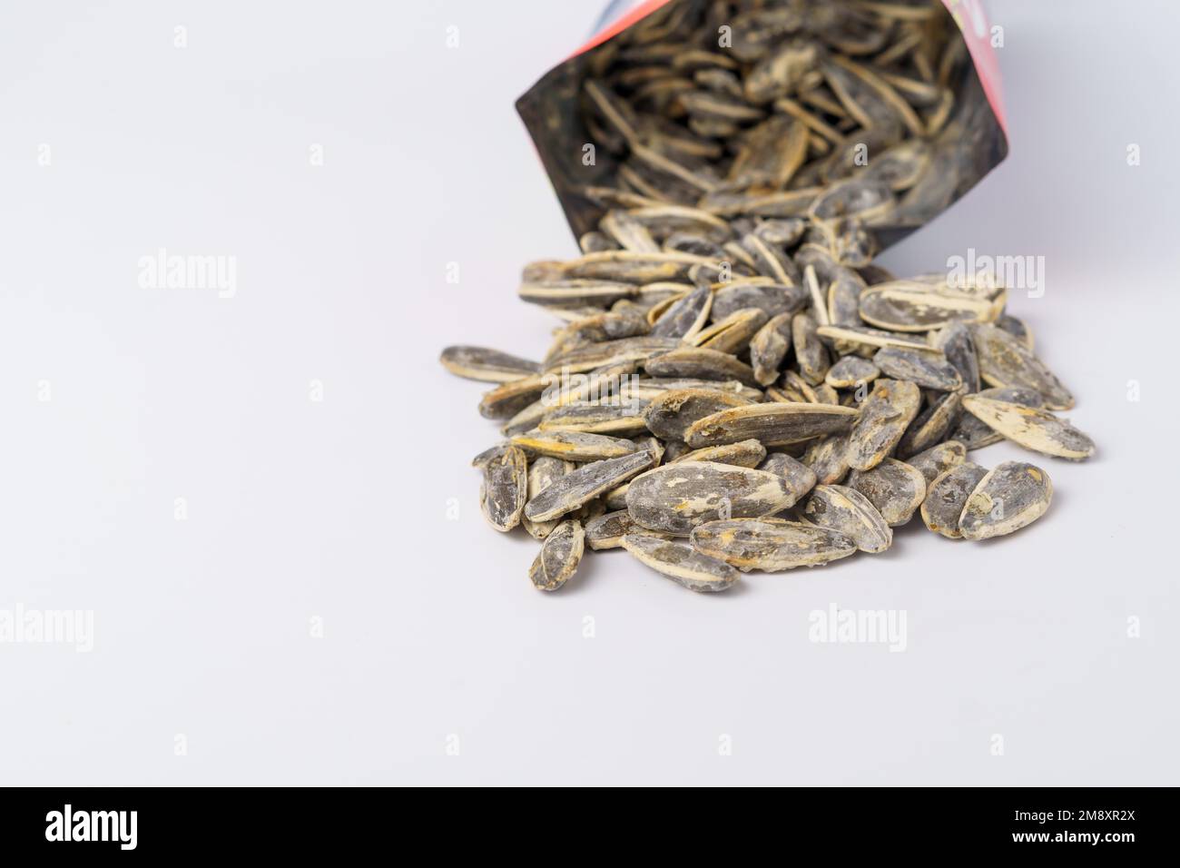 Roasted sunflower seeds with salt coming out of their bag on white ...