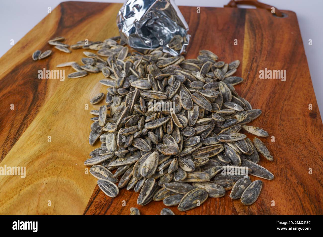 Roasted sunflower seeds with salt coming out of their bag on white ...