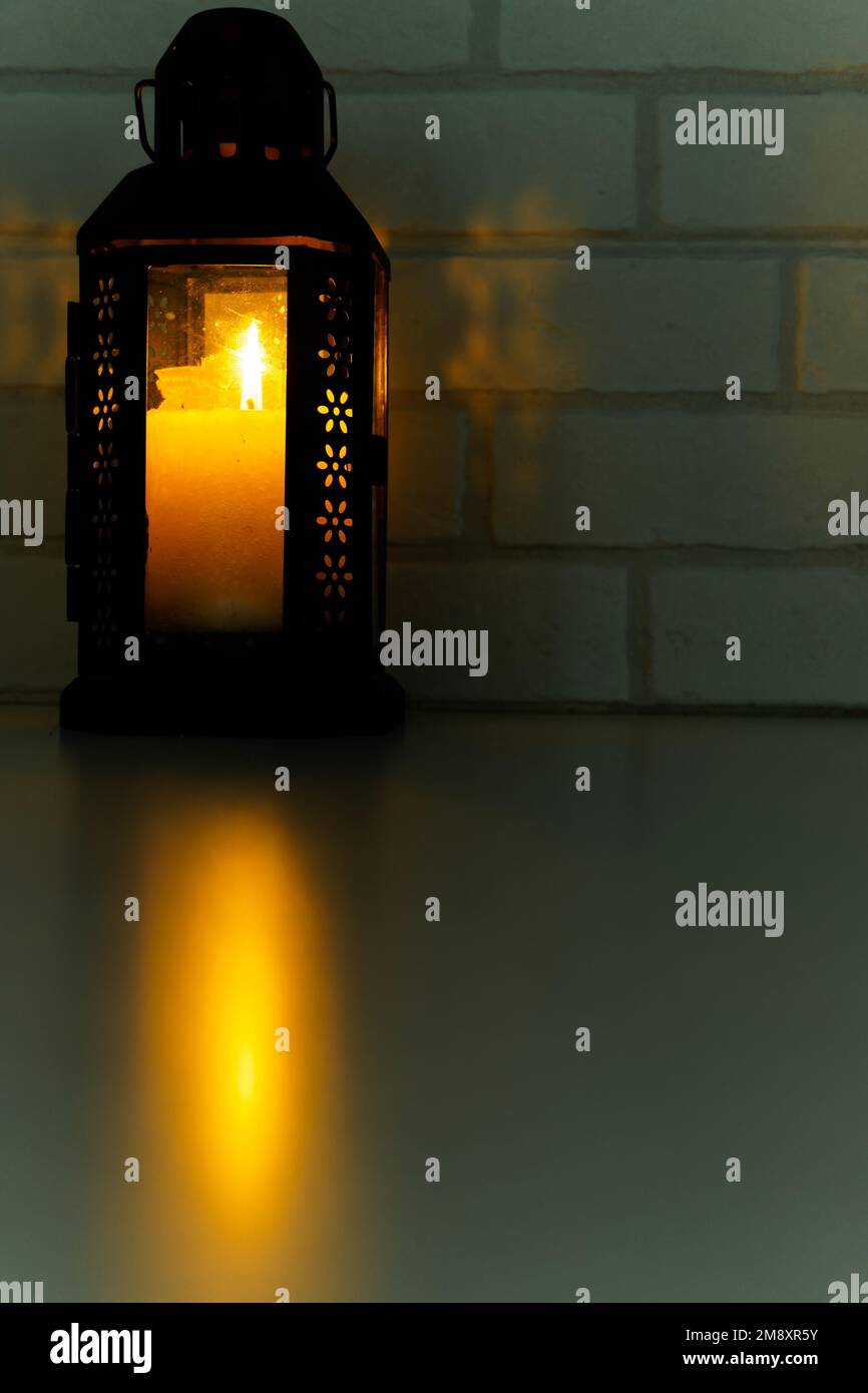 Lamp with lighted candle with light reflected on the table and brick ...