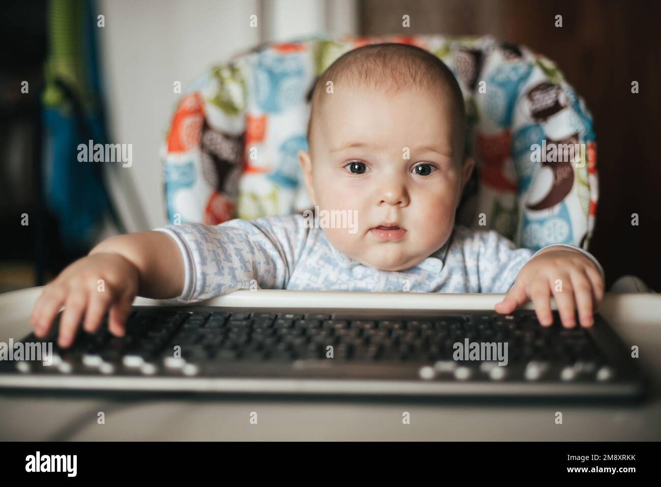 portrait of a cute little Caucasian baby boy sitting and playing with a ...