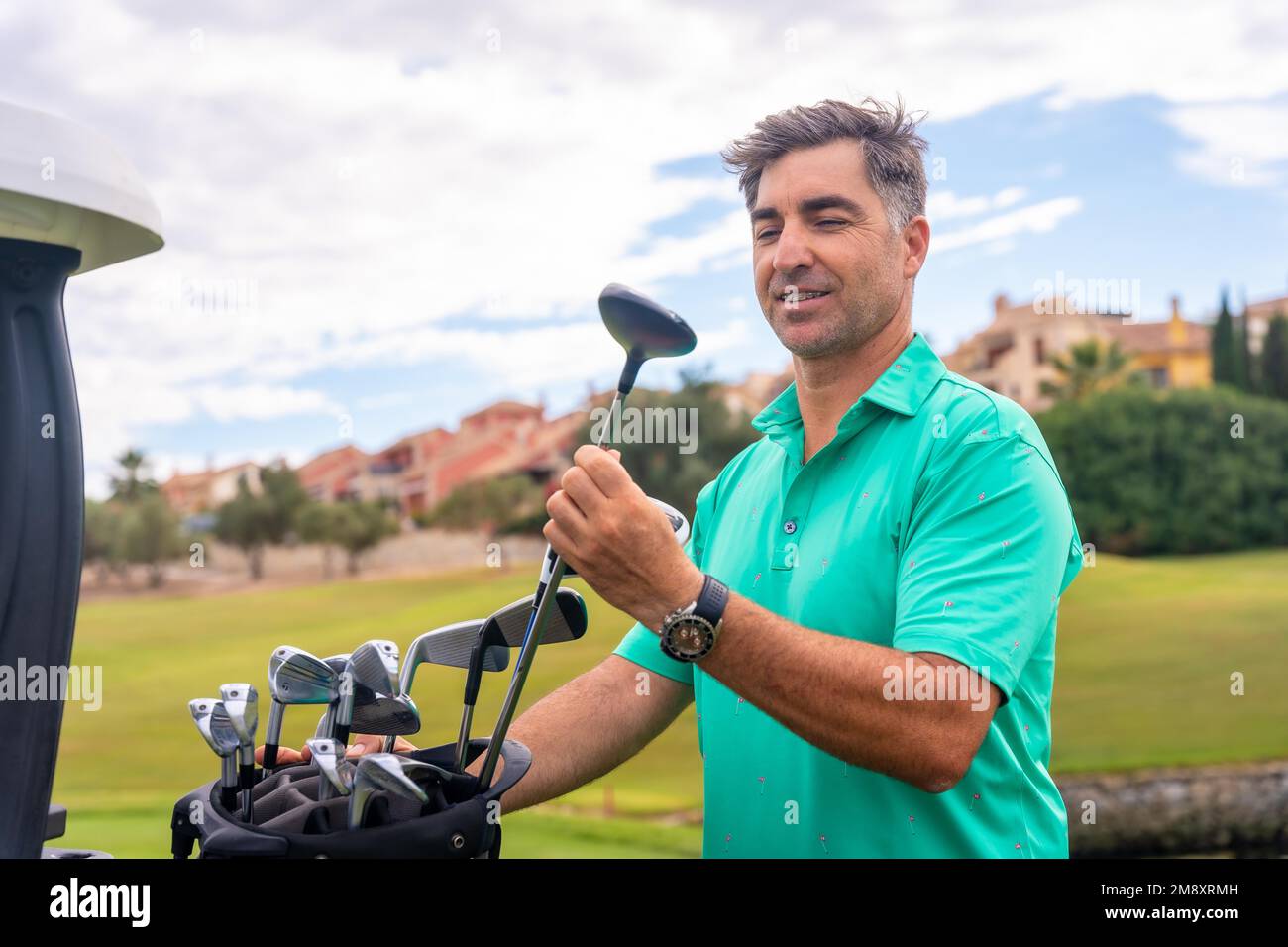 Man playing golf at golf club, checking golf clubs before hitting the ...