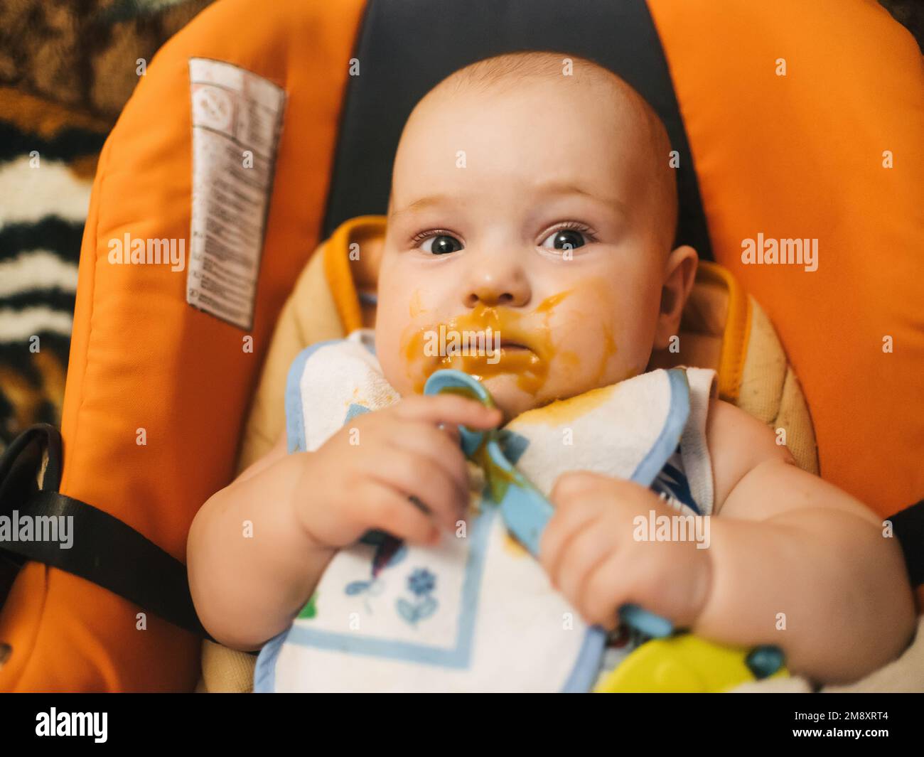 portrait of a little boy eating a baby with a spoon and a grimy face ...