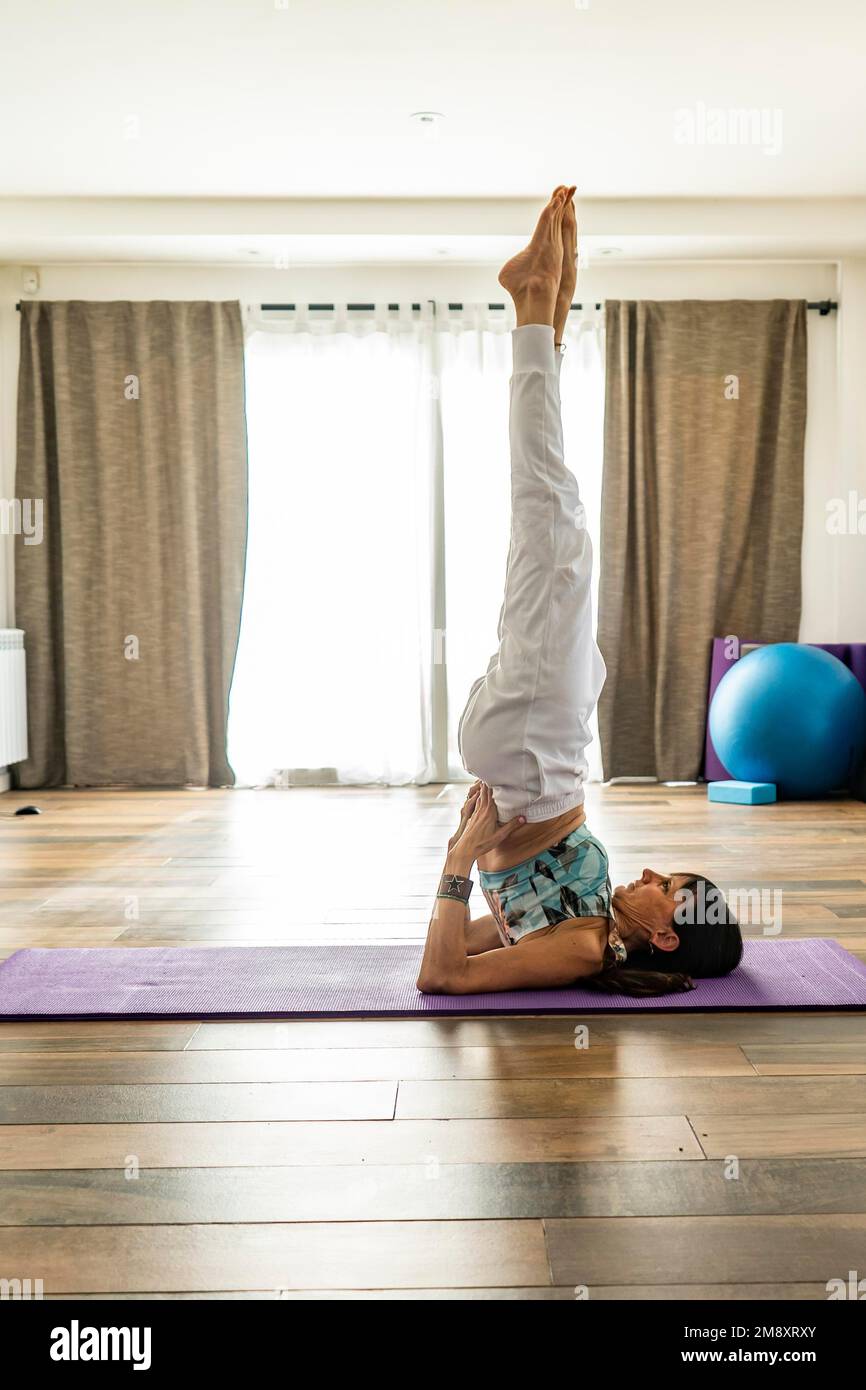 Side view of a woman practicing yoga, doing Shoulderstand pose. Yoga ...