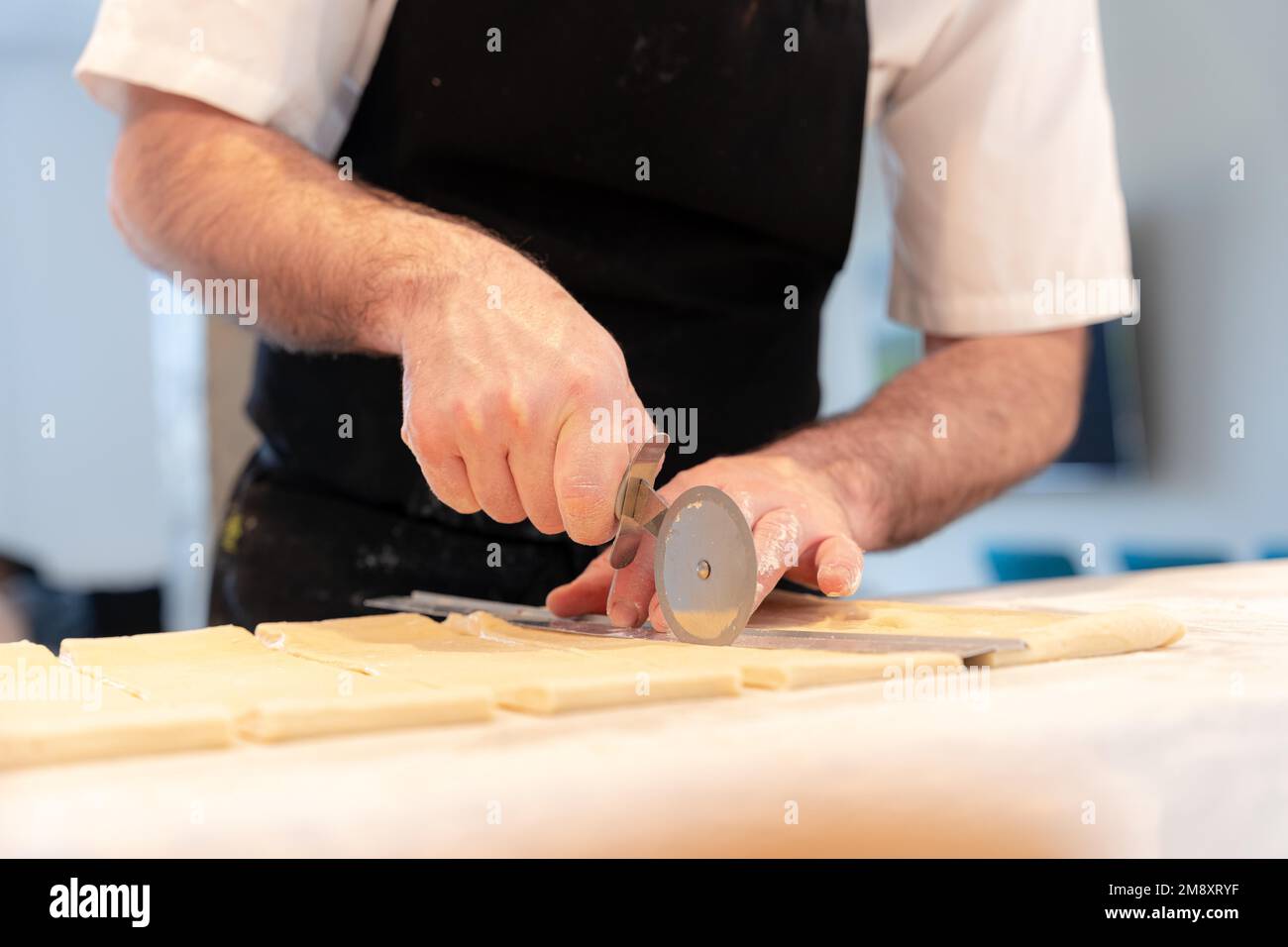 Detail of the hands of a man baking croissants, measuring the puff ...