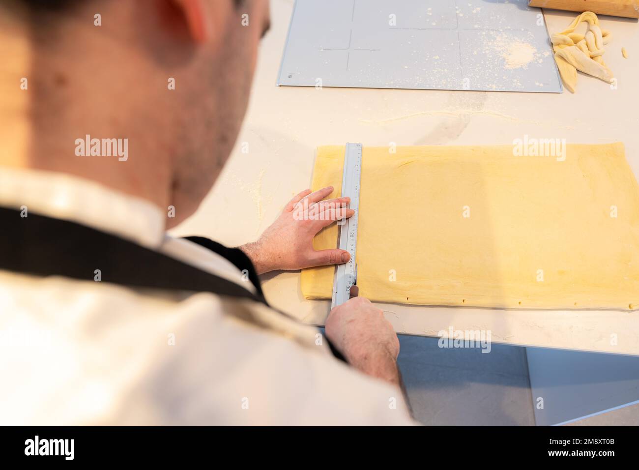 Man baking homemade croissants, measuring puff pastry and making cuts ...
