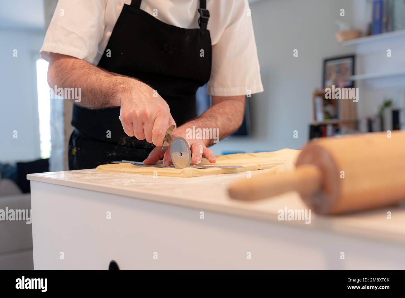 Detail of the hands of a man baking croissants, measuring the puff ...