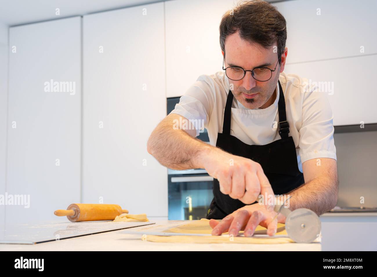 Man baking homemade croissants, measuring puff pastry and making cuts ...