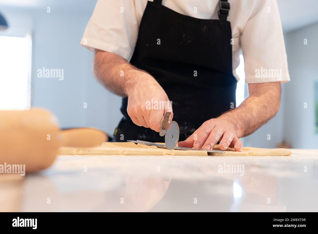 Detail of the hands of a man baking croissants, measuring the puff ...