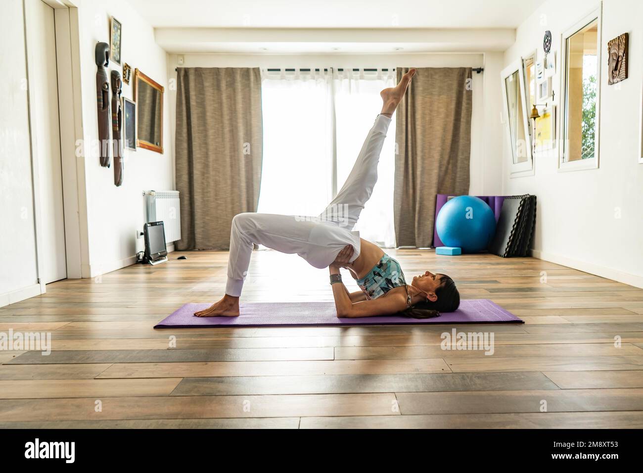 Side view of a woman practicing yoga, doing One Legged Bridge Pose (Eka ...