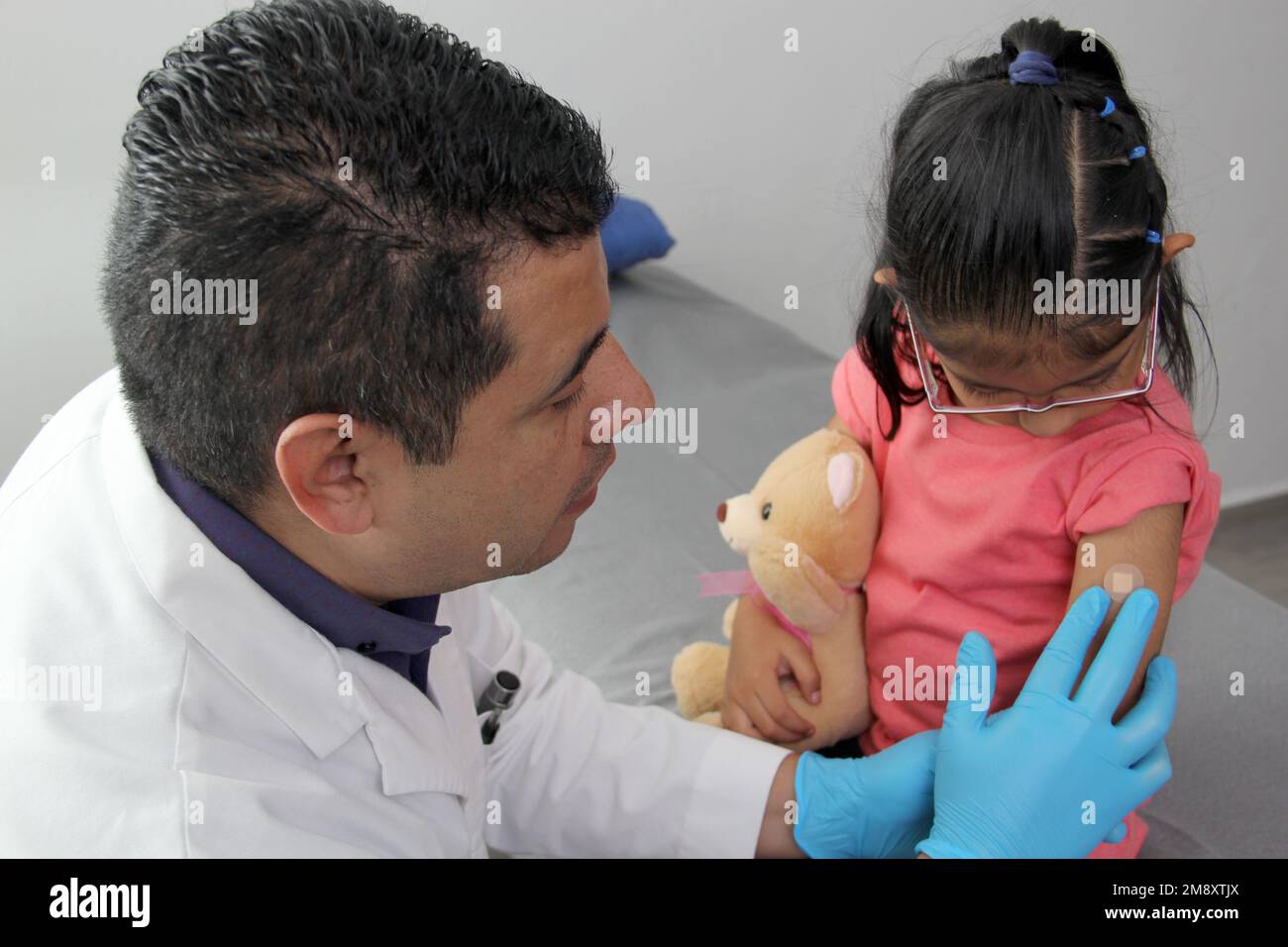 Dark-haired Latino doctor and little girl have a medical consultation ...