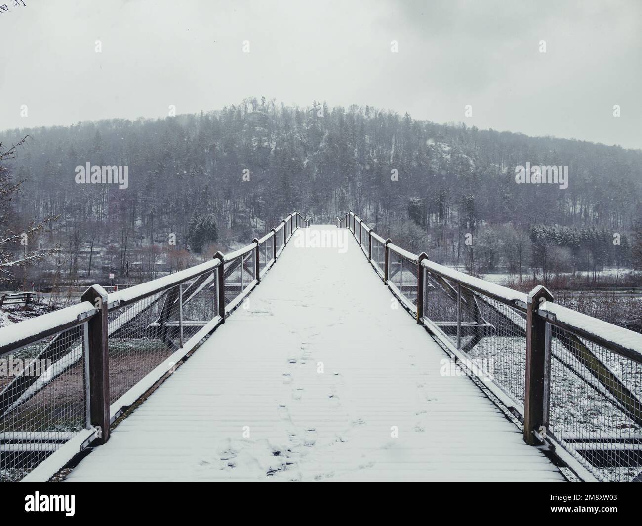 A snow-covered bridge with a forest in the background on a cold winter ...