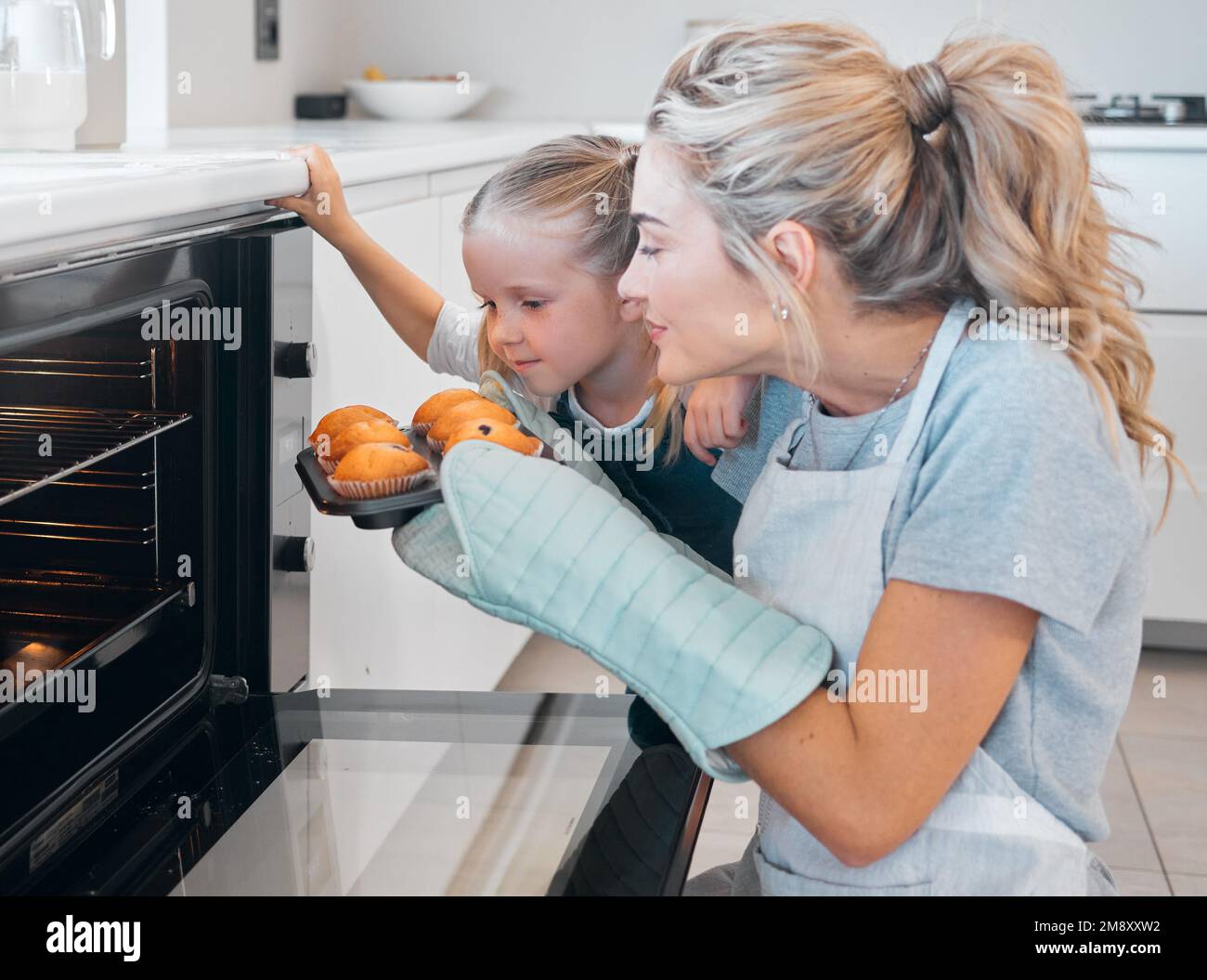 Young mother smelling a tray of fresh baked muffins. Caucasian woman ...