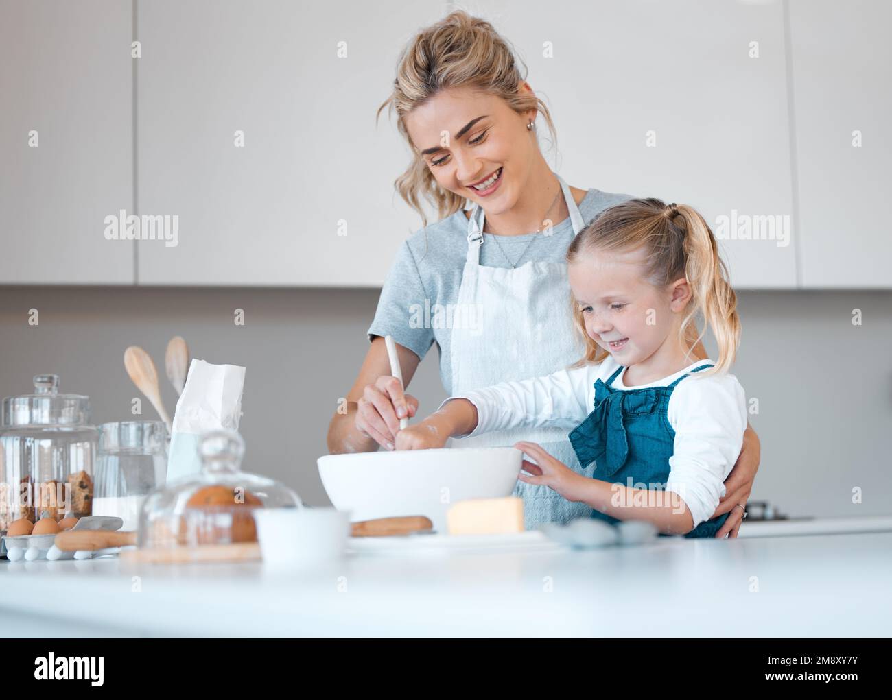 Happy mother helping her daughter bake. Parent baking with her child ...