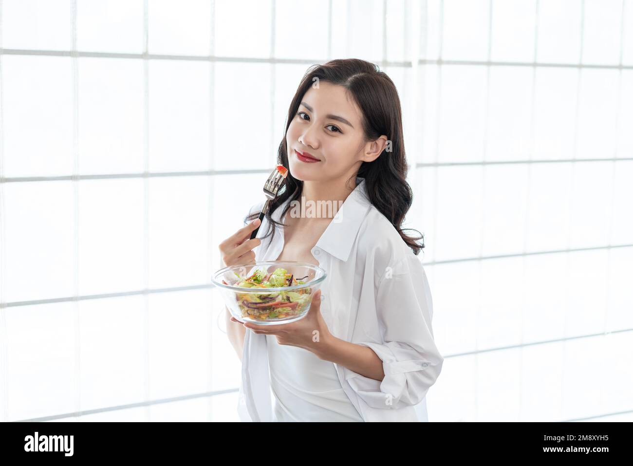 A young woman sit by the window eating salad Stock Photo - Alamy