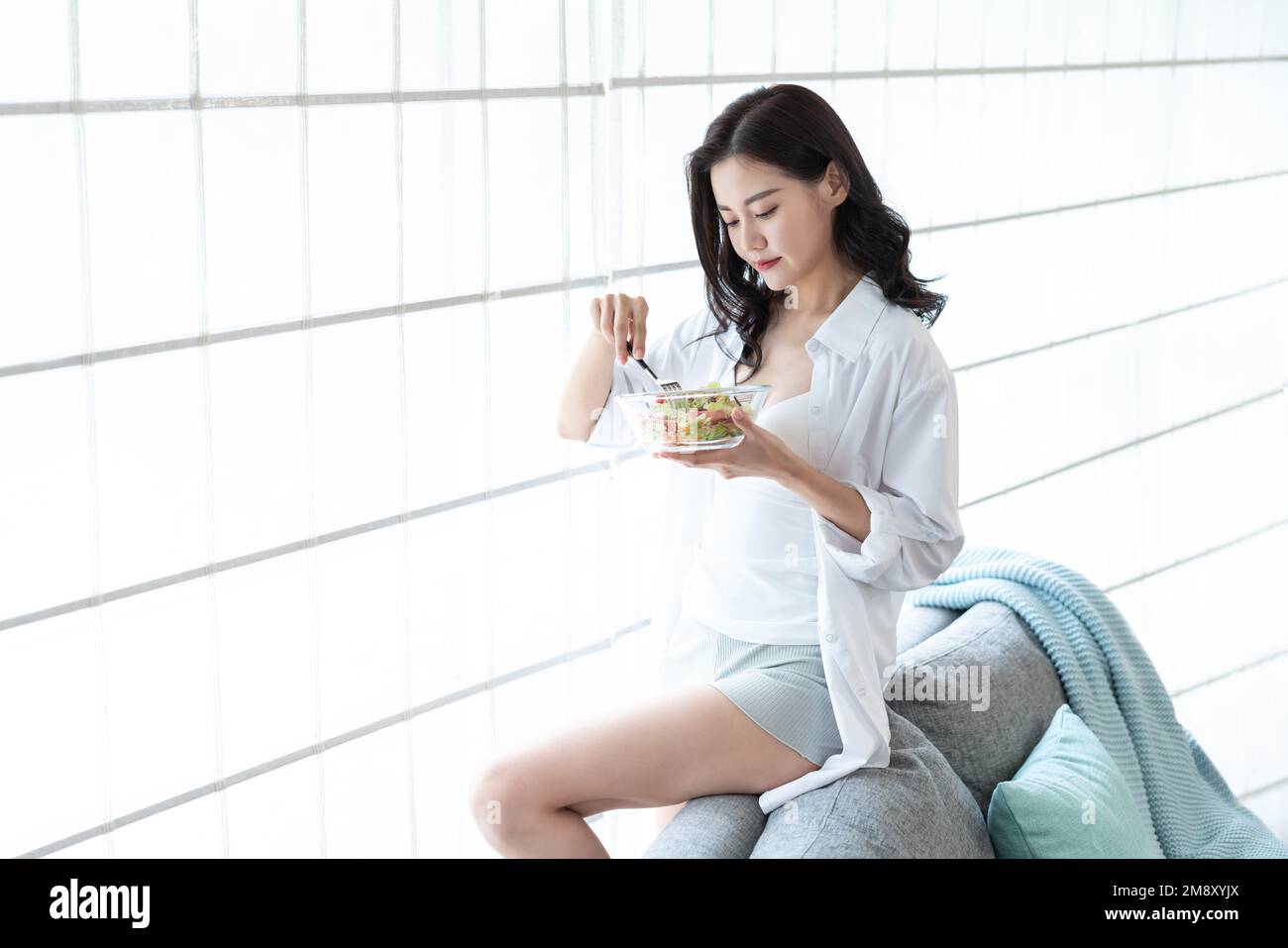 A young woman sit by the window eating salad Stock Photo - Alamy