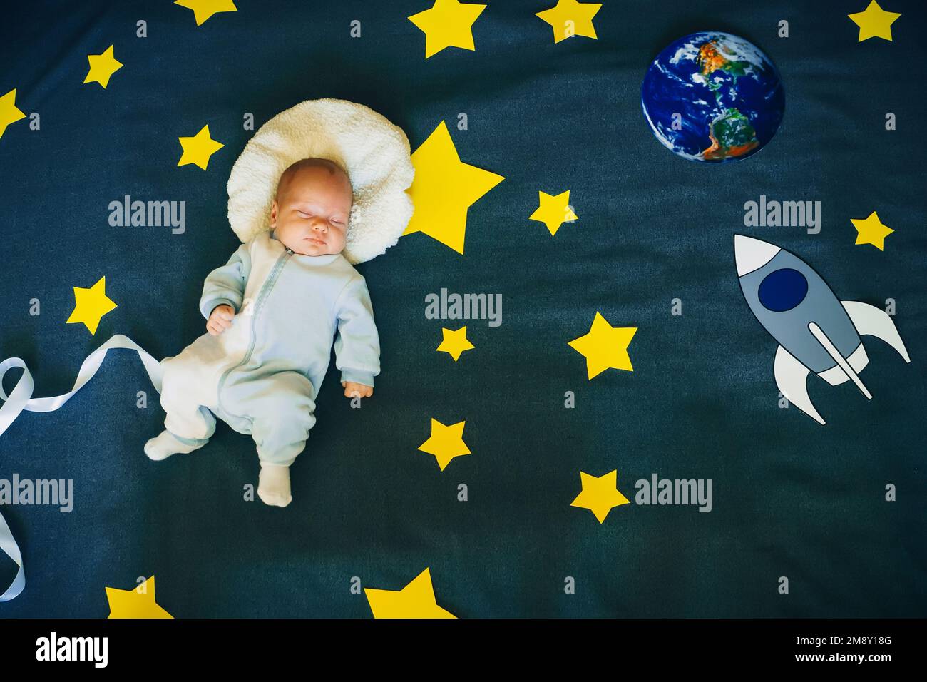 little boy baby sleeping in a suit of the astronaut on the background ...