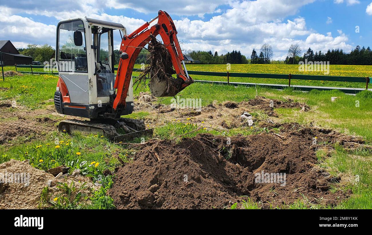 Work on the construction site of a house. The excavator digs out roots ...