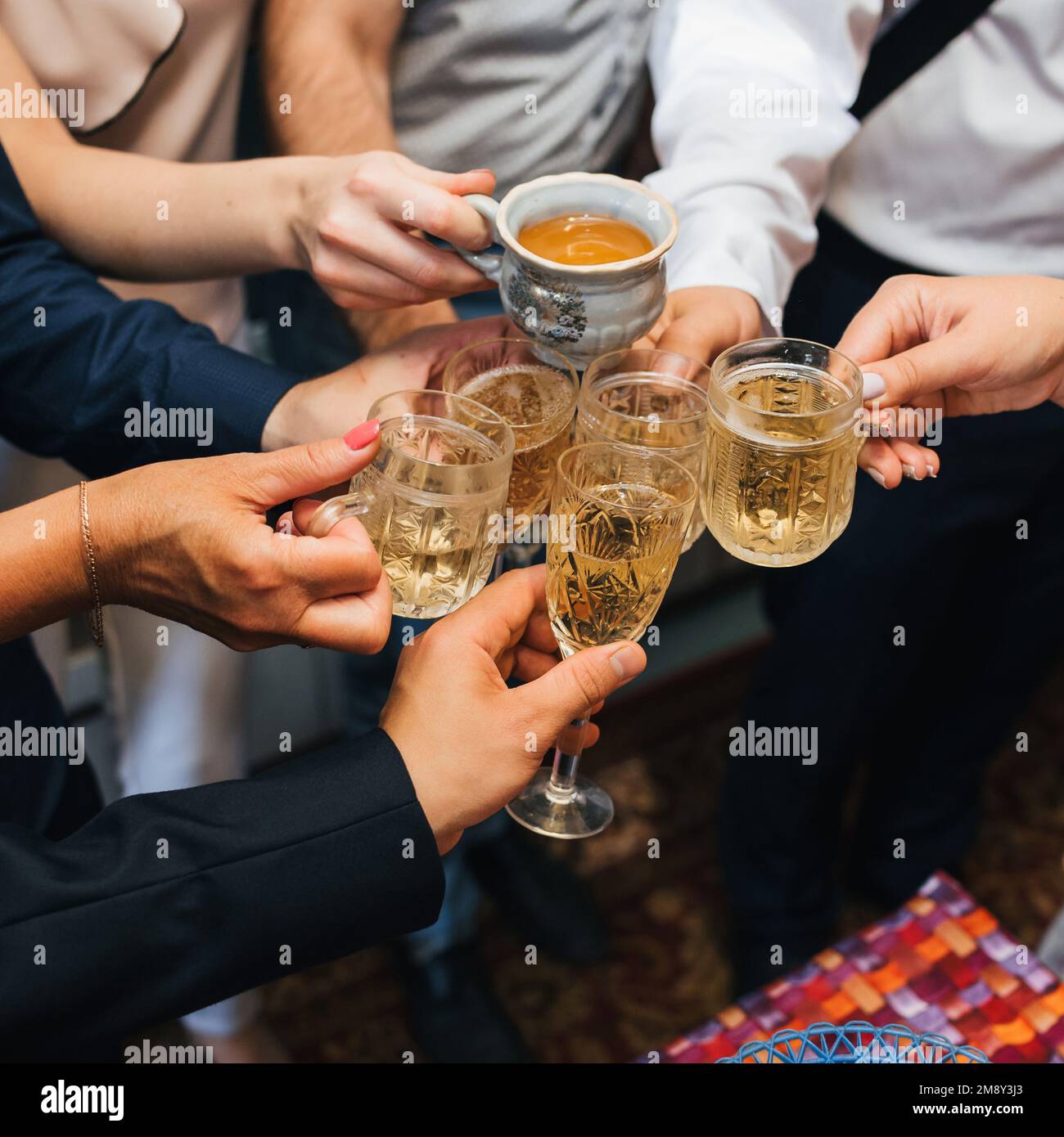 hands of a group of friends clinking glasses of alcoholic beverage and ...
