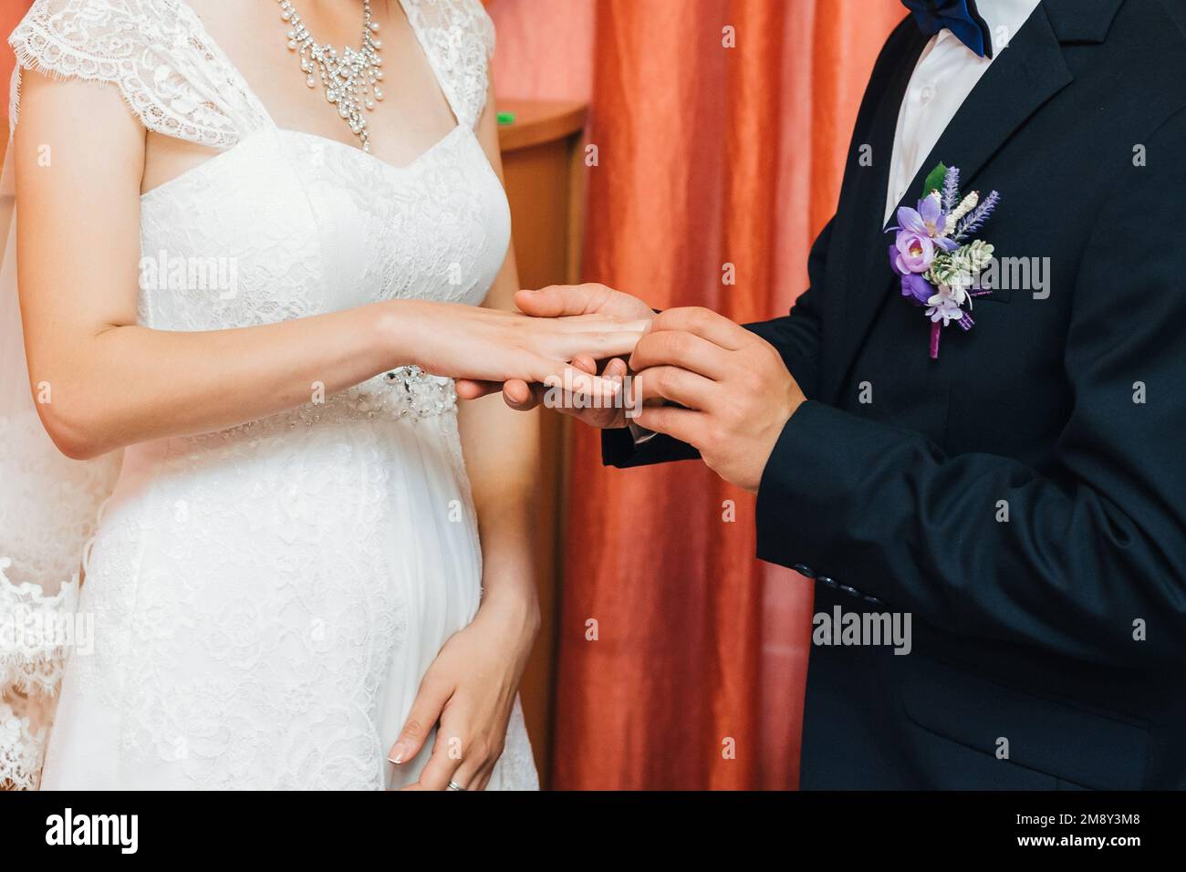 groom puts a gold wedding ring on the bride's finger. Traditional ...