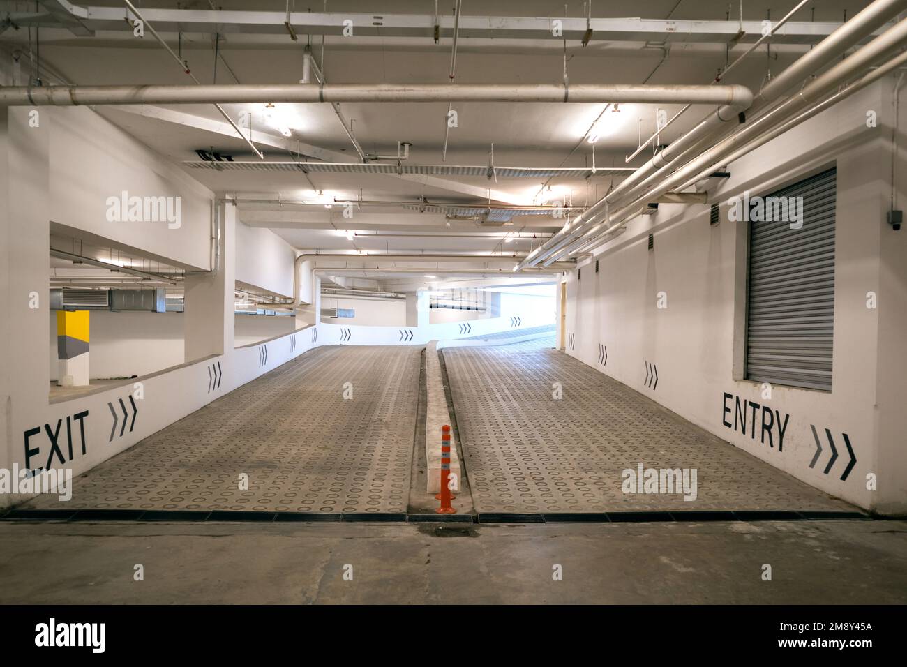 A concrete vehicle ramp inside a building with entry and exit signs ...