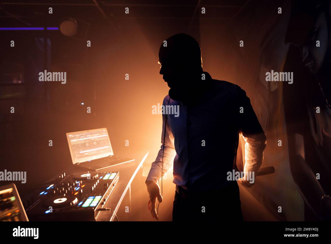 silhouette of a DJ with a microphone at the mixer on the nightclub ...