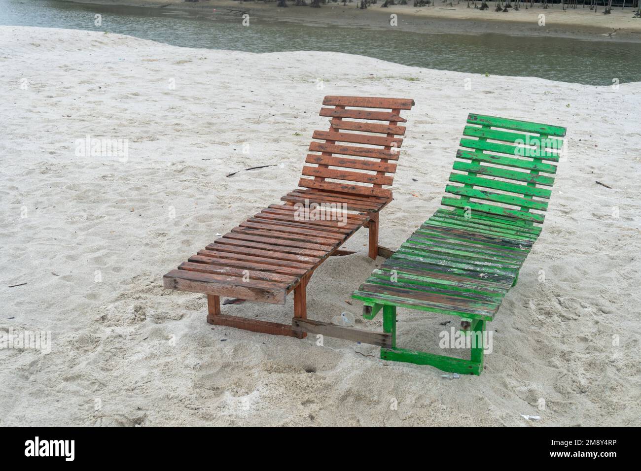 Wooden lounge chairs on the white sand beach in the middle of nature ...