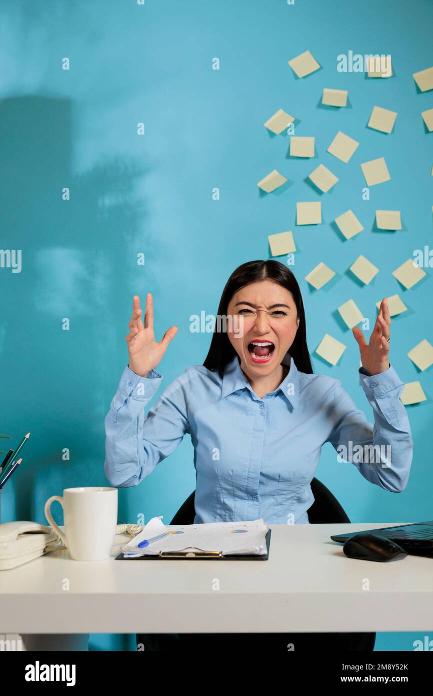 Female corporate employee screaming and waving her arms sitting at ...