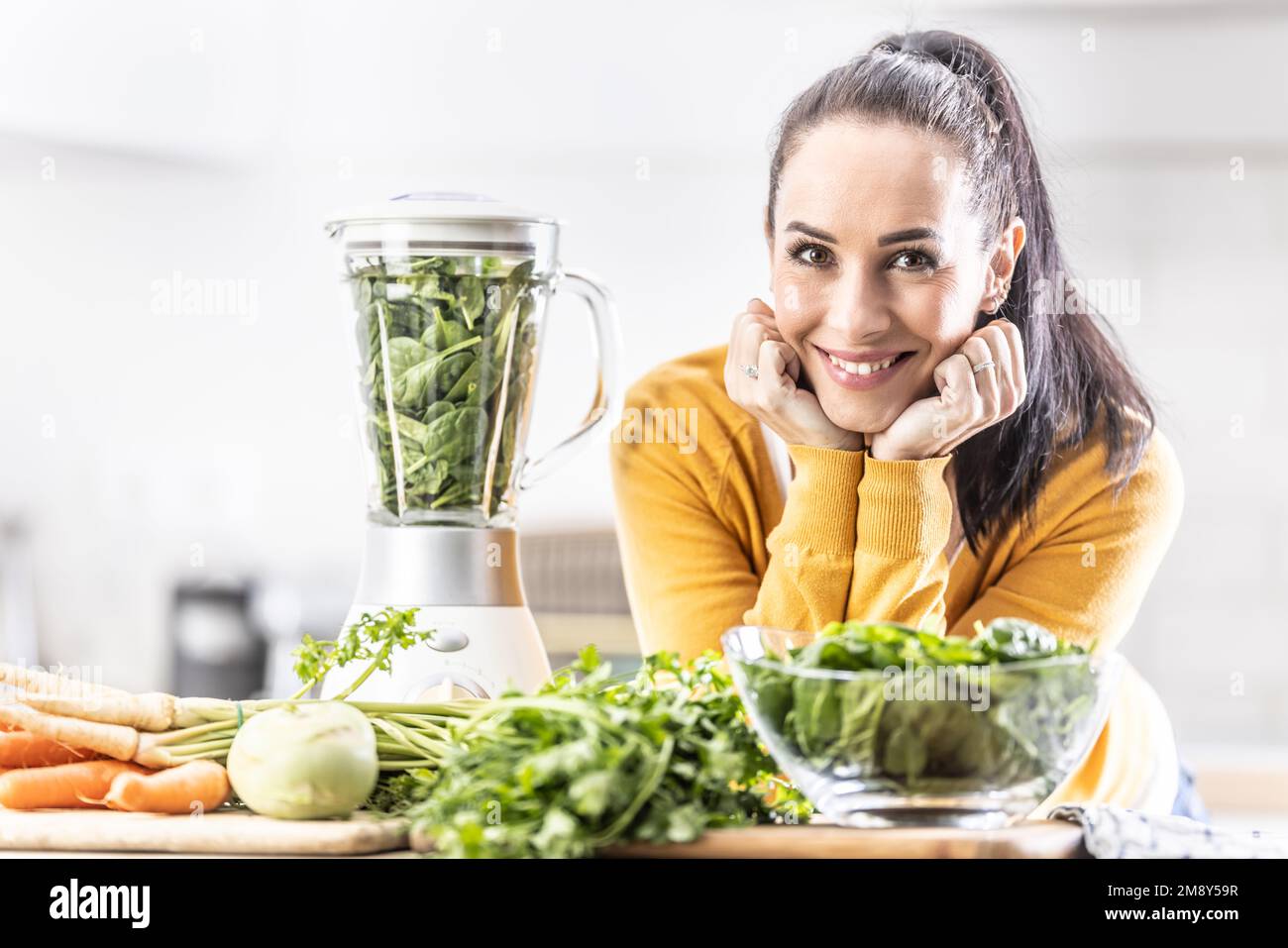 A Young Woman Prepares An Energy Drink From Fresh Vegetables Using A