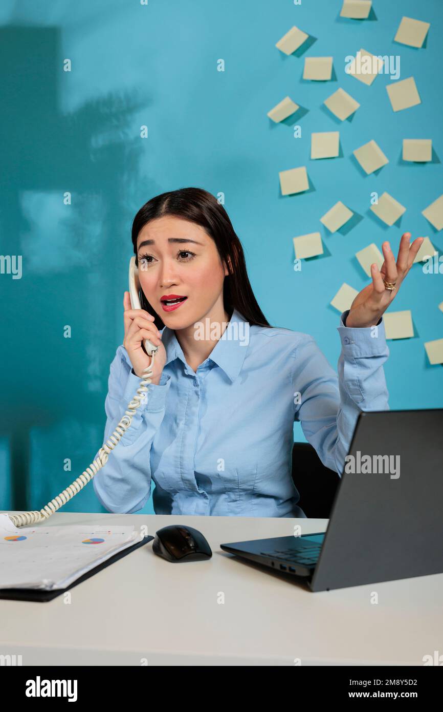 Corporate female employee sitting at a desk in the workplace holding a ...