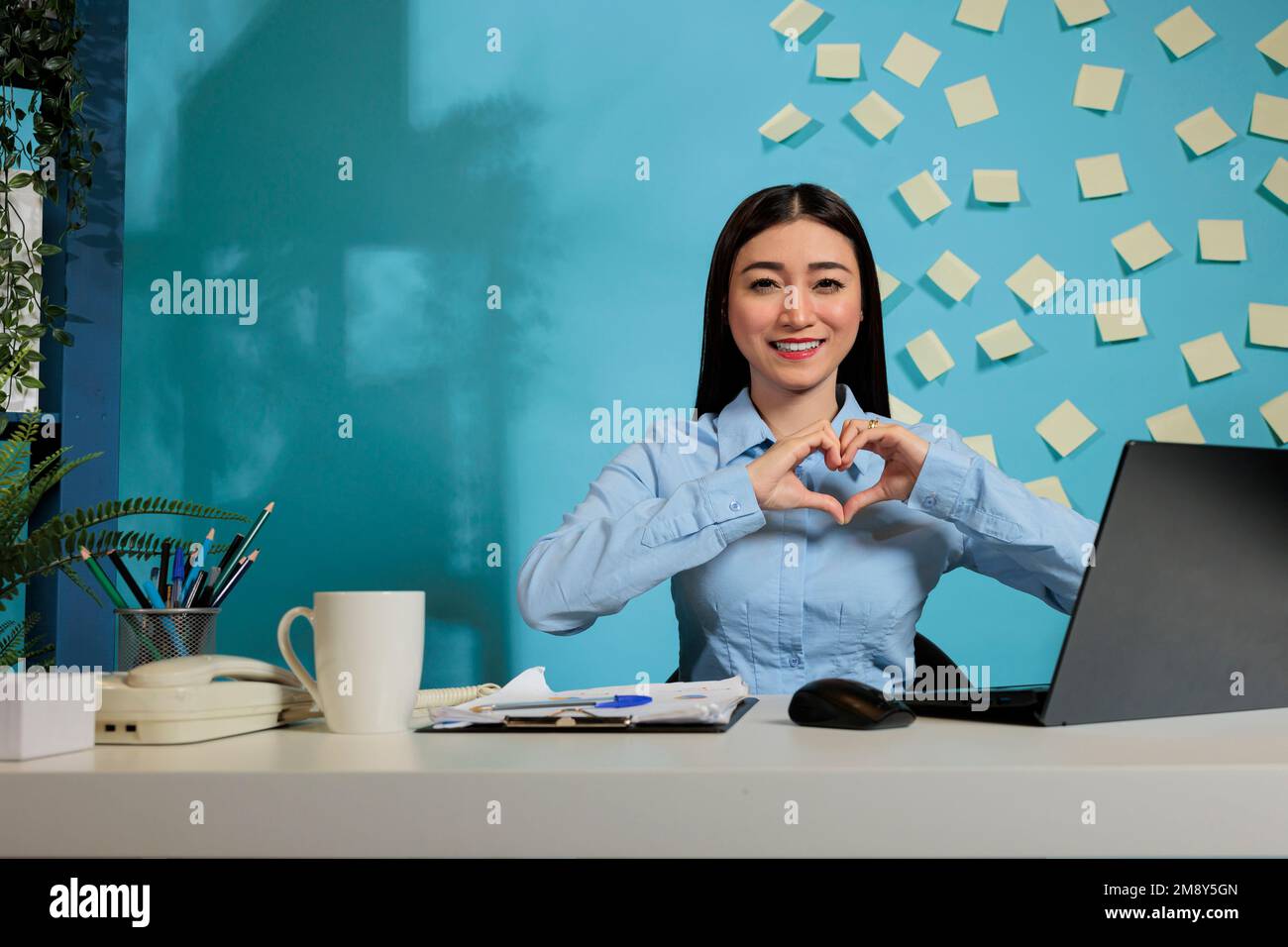Friendly professional woman making a heart shaped sign indicating ...