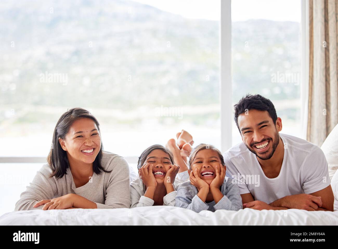 Young couple looking happy and relaxed while sharing the bed with their ...