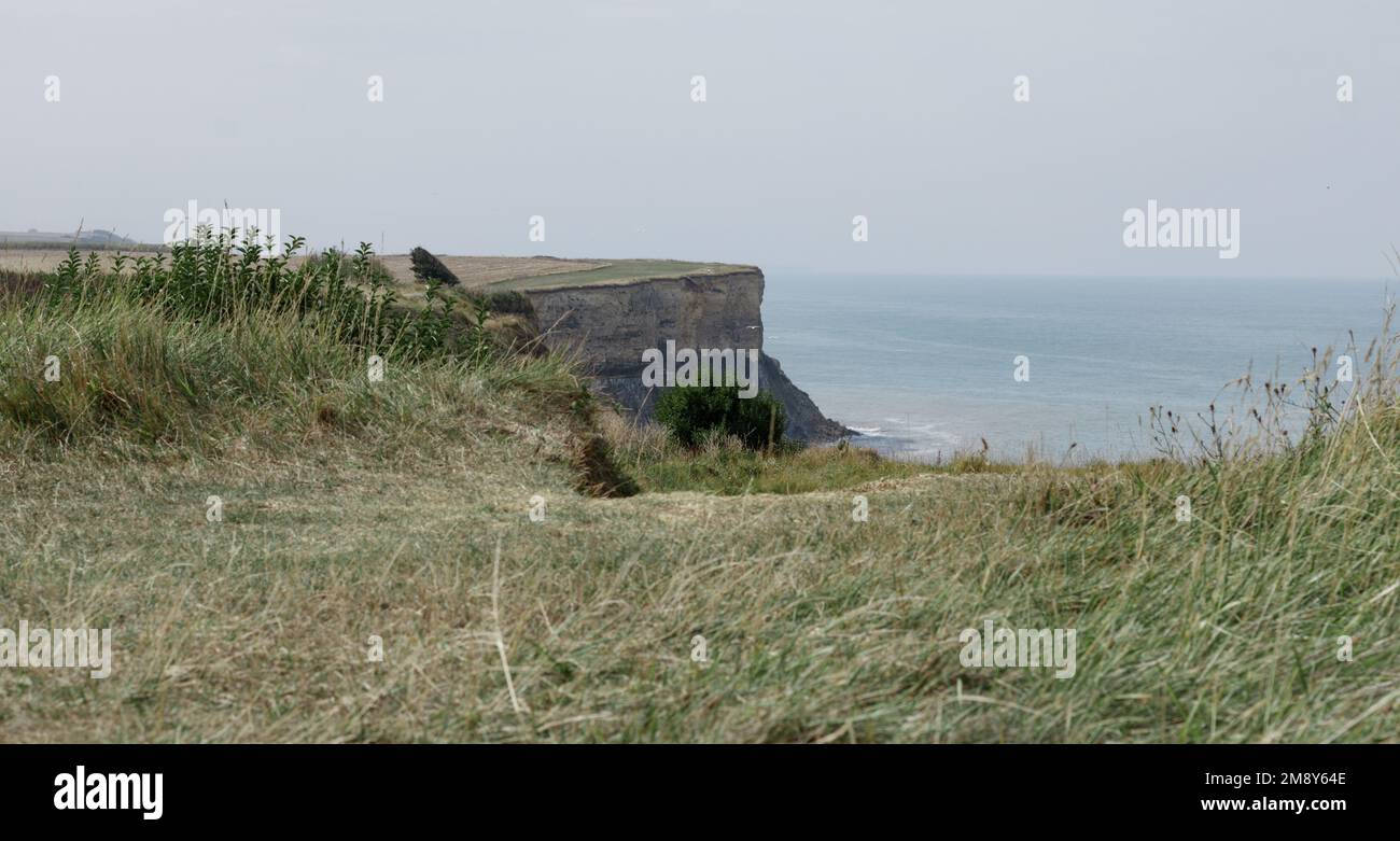 A rocky cliff with grass on the foreground against a hazy horizon Stock ...