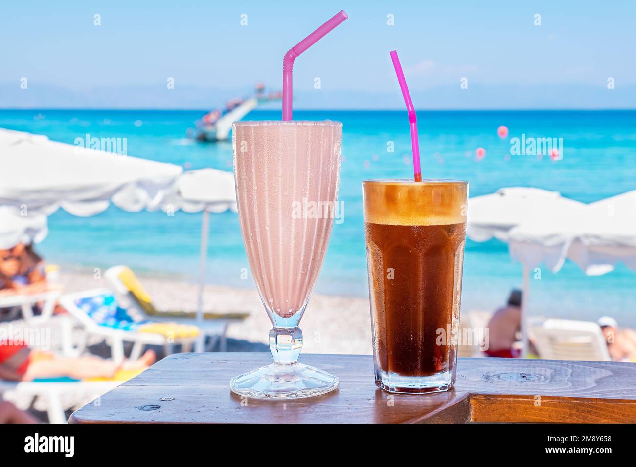 Glasses with milkshake and frappe on a table with view of the beach ...