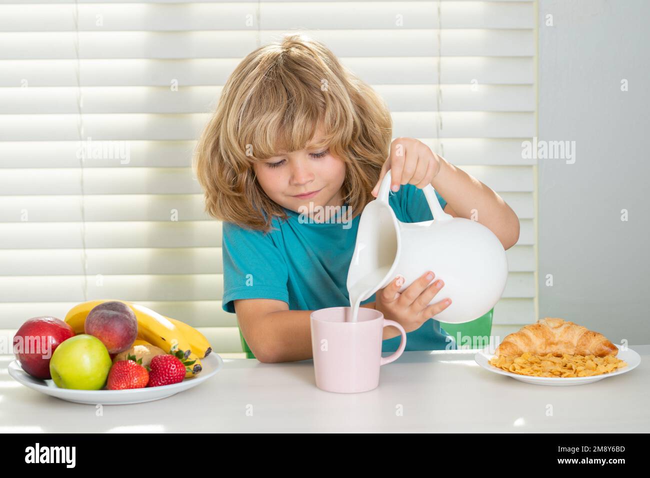 Kid pouring whole cows milk. Schoolkid eating breakfast before school ...