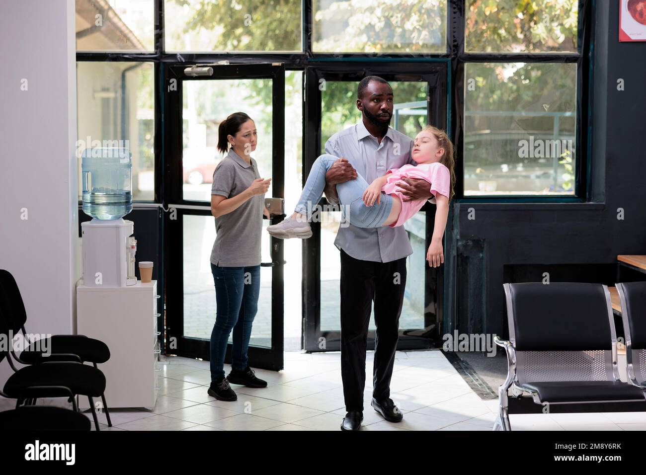 Worried african american dad holding unconscious daughter in arms after ...