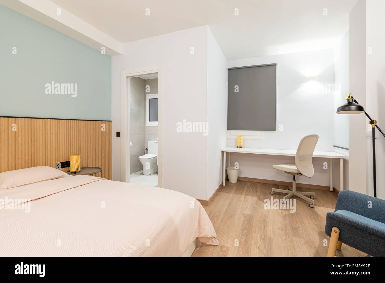 View of bedroom with large bed, work area with white wooden table and ...