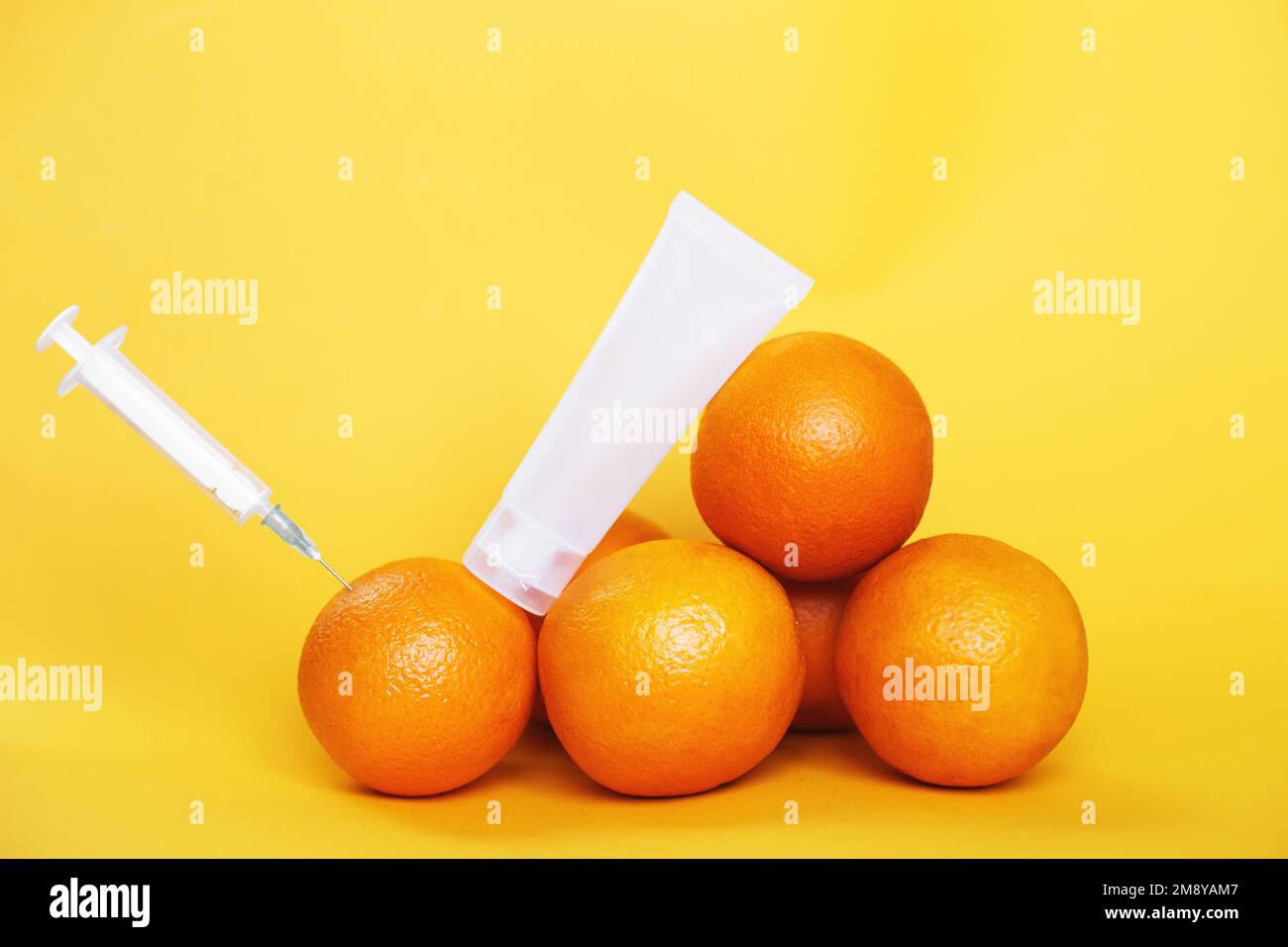 orange fruit with syringe extracting liquid with vitamin C and empty ...