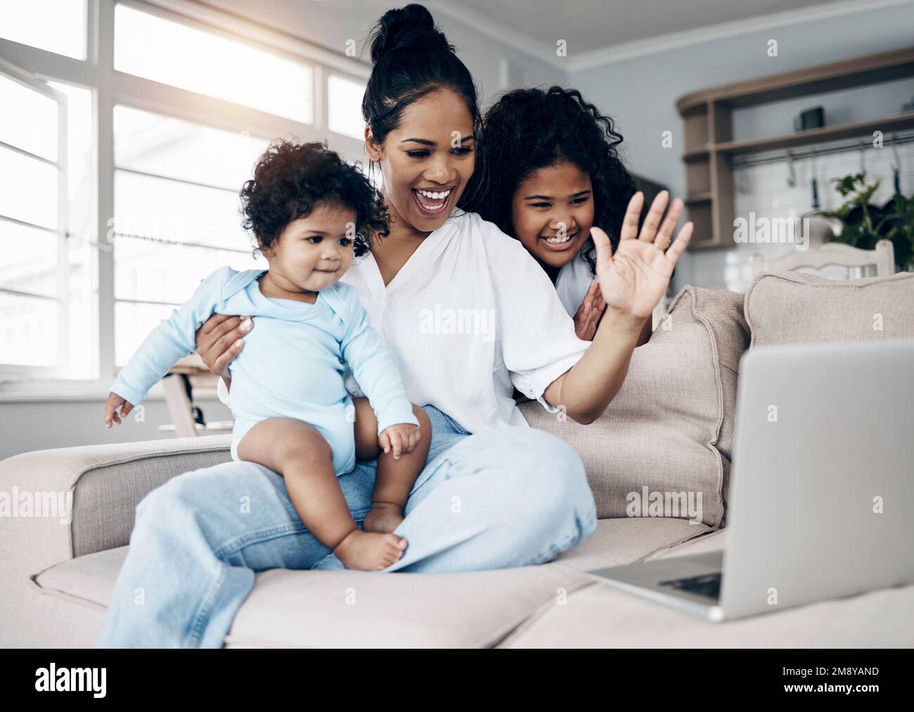 Hi over there. a young mother using a laptop with her daughters on the ...