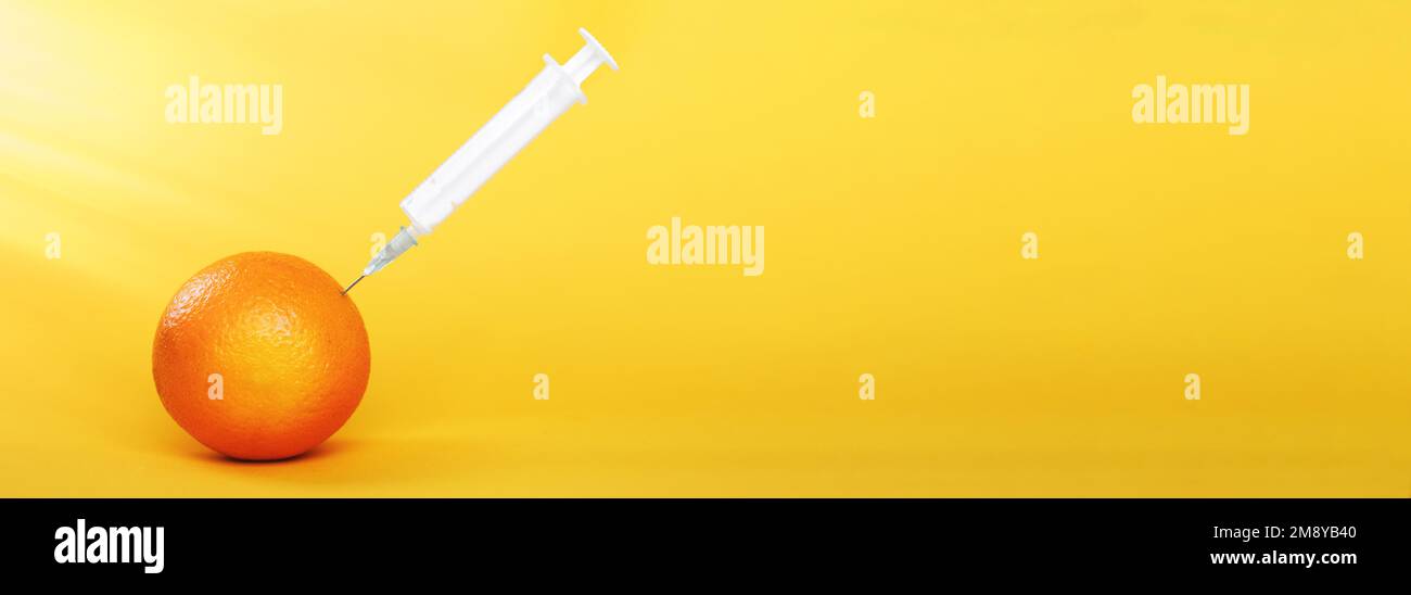orange fruit with syringe extracting liquid with vitamin C. natural ...