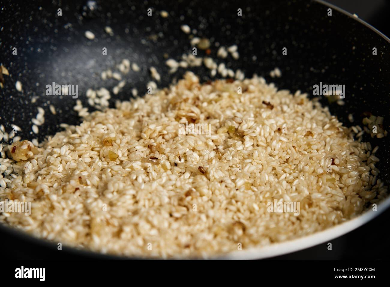 Process of cooking risotto. Arborio rice in frying pan at home kitchen ...