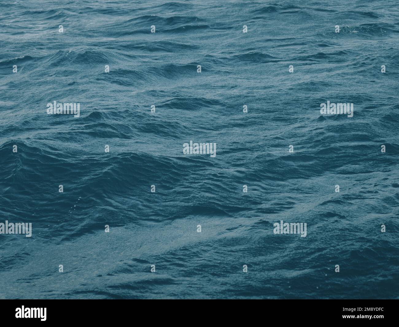 Dark blue-green color of water surface with waves in middle of endless ...