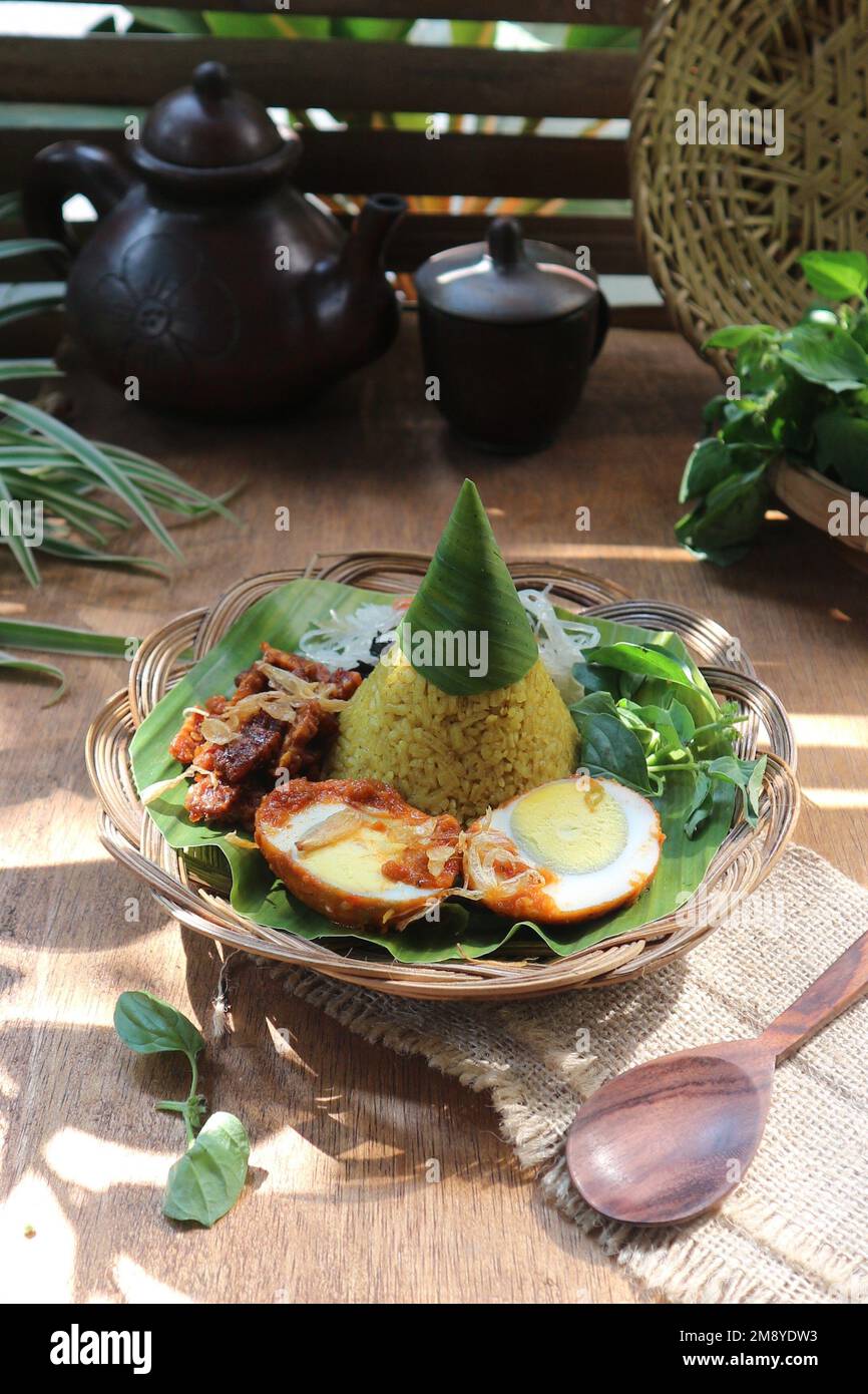 Indonesian cone shape rice with seasoned eggs served on a rattan plate ...