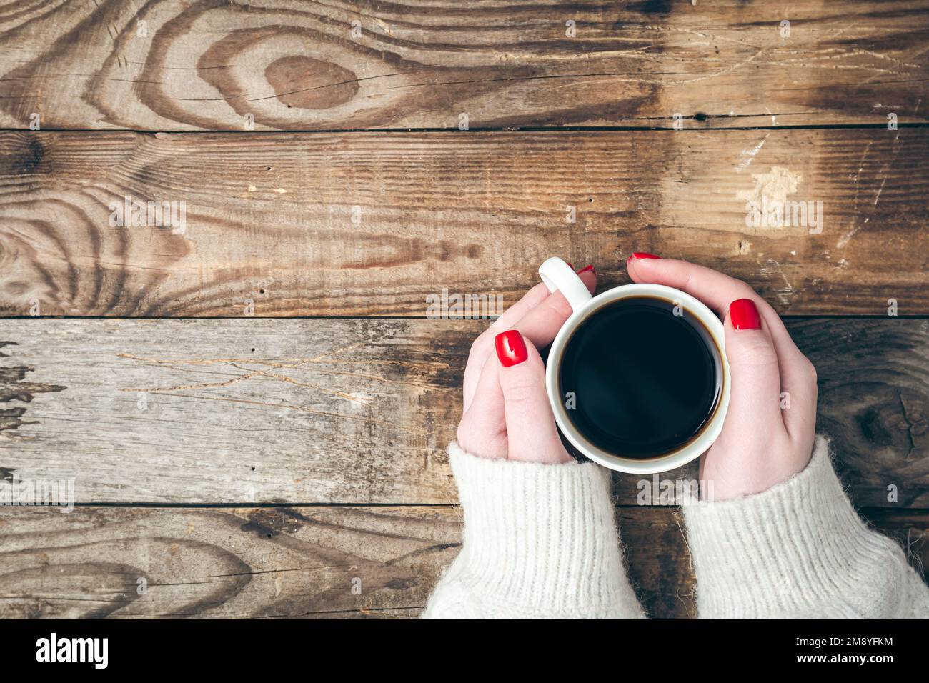 Female hands hold a cup of coffee on a wooden background, flat lay ...