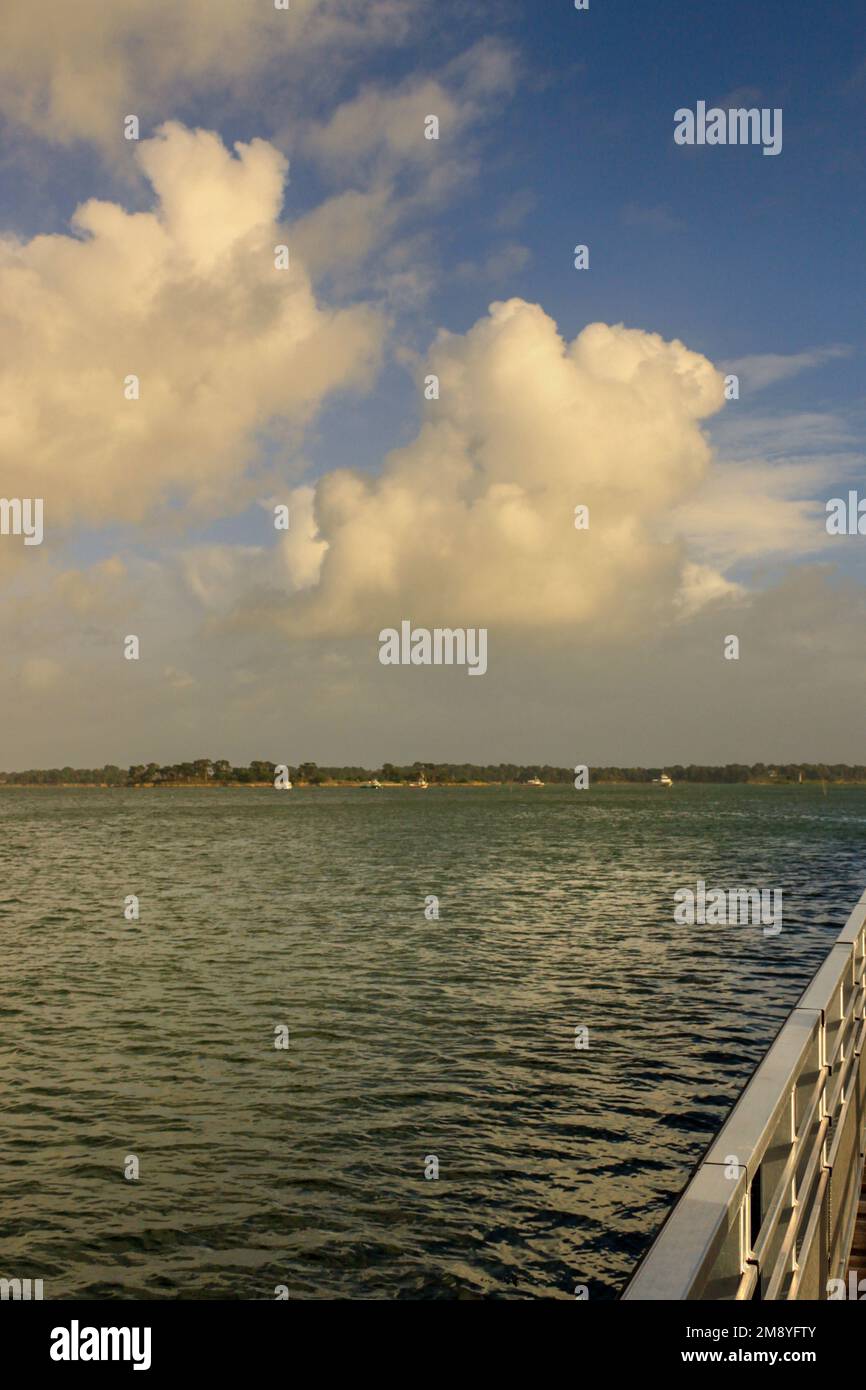 The calm bay and in the distance an island. The sky is blue with a few ...