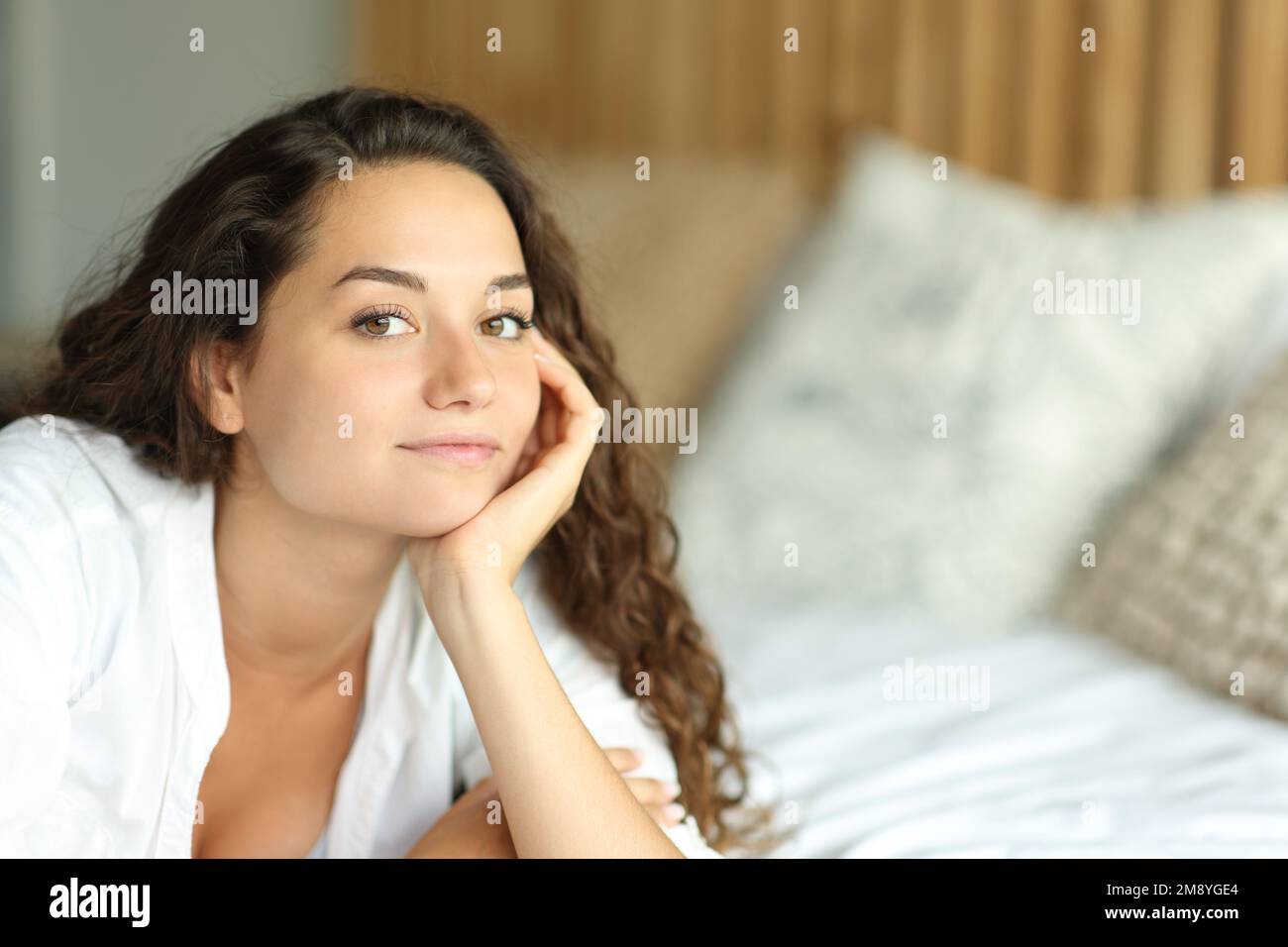 Relaxed woman looking at camera lying on the bed in a bedroom Stock ...