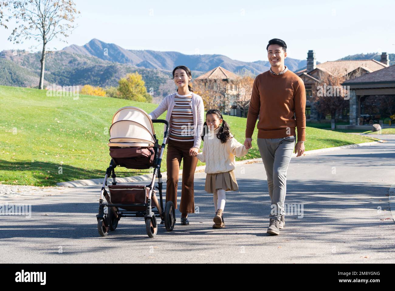 A young couple walk pushing a stroller Stock Photo - Alamy