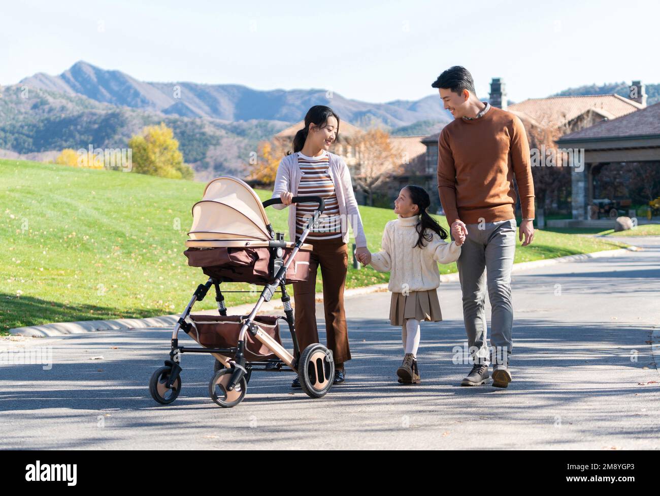 A young couple walk pushing a stroller Stock Photo - Alamy