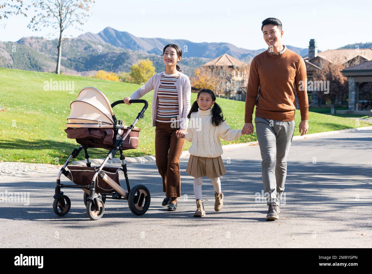 A young couple walk pushing a stroller Stock Photo - Alamy