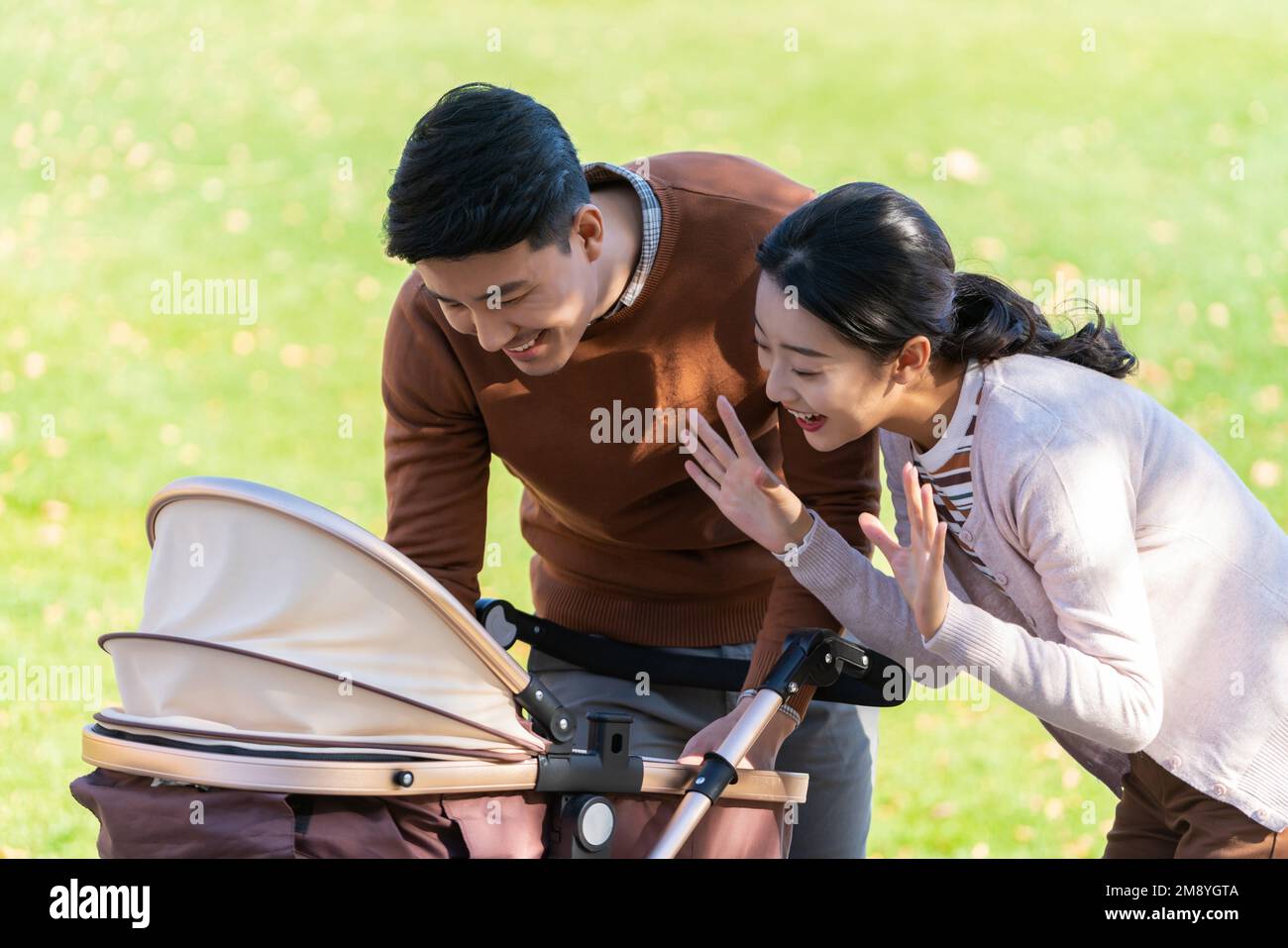 A young couple walk pushing a stroller Stock Photo - Alamy